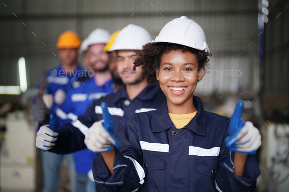 Young confident leader of team standing in front of factory workers ...