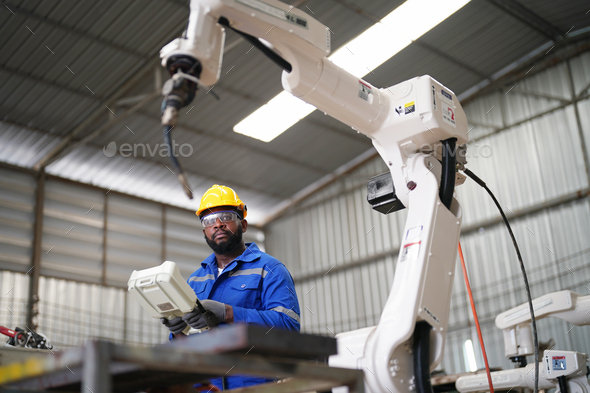Robotics engineer operating robot aided CNC machine in robotics ...