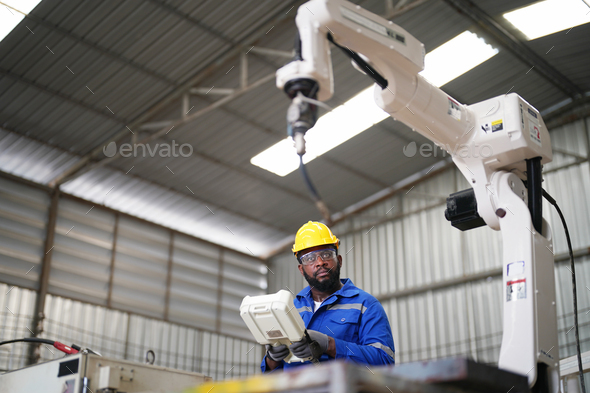 Robotics engineer operating robot aided CNC machine in robotics ...