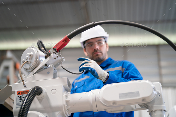 Robotics engineer operating robot aided CNC machine in robotics ...