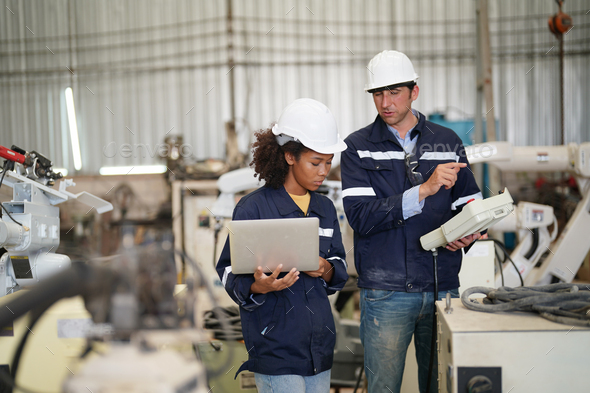 Robotics engineer operating robot aided CNC machine in robotics ...
