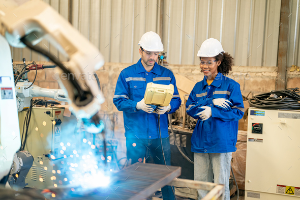 Robotics engineer operating robot aided CNC machine in robotics ...