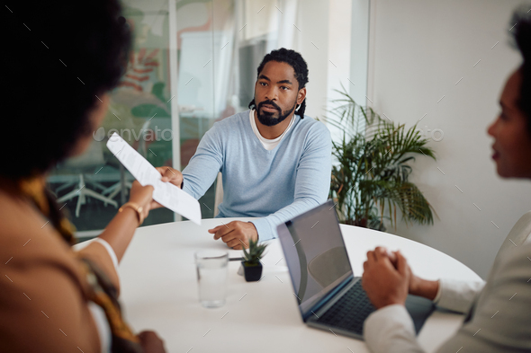 African American candidate giving his resume during job interview in ...