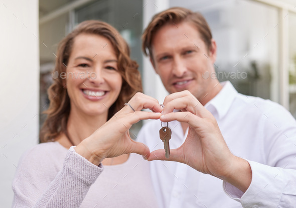 Closeup hands of happy married couple holding up new house keys with a ...