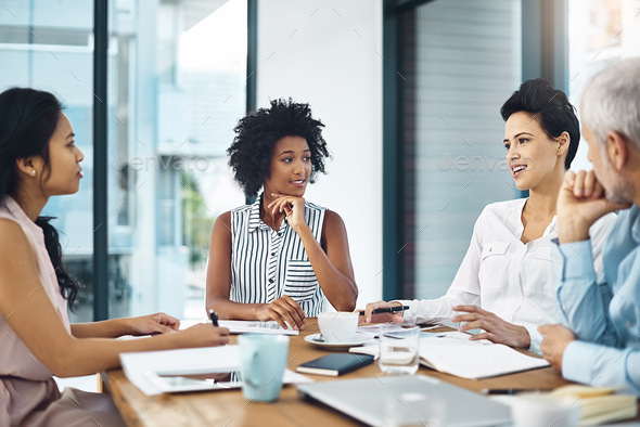 Shot of a group of coworkers talking together in a meeting in an office ...