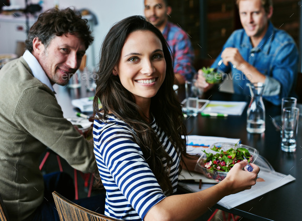 Portrait of a young office worker eating lunch with coworkers at a ...