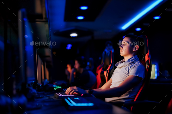 Focused teenager using computer at internet cafe, side view, portrait ...