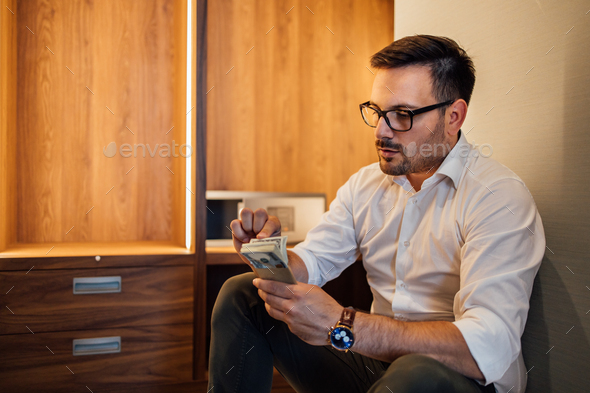 Focused businessman counting money before put it into safe box ...