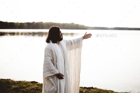 Shallow focus shot of Jesus Christ with his hands up and looking in the ...