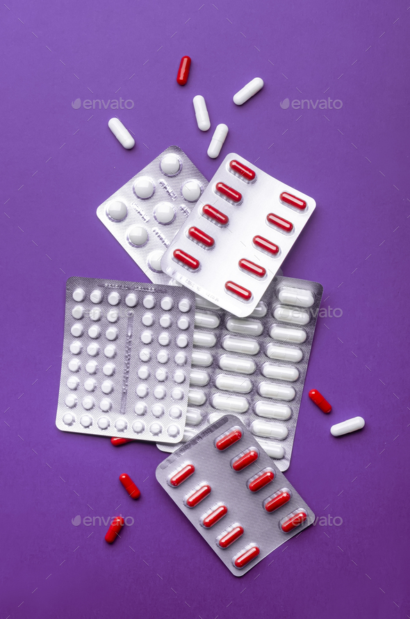 Tablets, pills and red white capsules packed and scattered. Top view ...