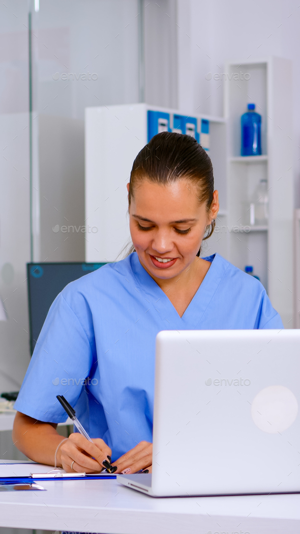 Nurse taking notes on clipboard after reading medical raports from ...