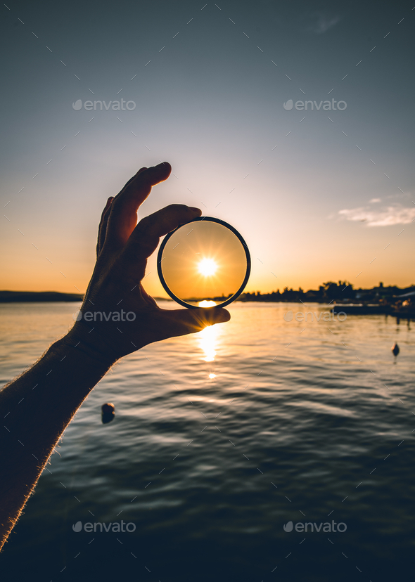 Male hand holding a magnifying glass on the sea and sun Stock Photo by ...
