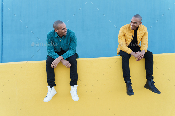 African American adult identical twin brothers and smiling, sitting on ...