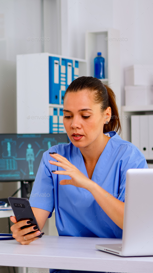 Nurse holding smartphone talking to patient making telemedicine Stock ...
