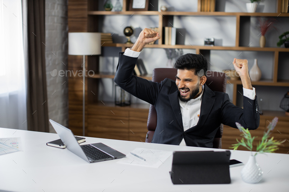 Excited screaming young business man triumphing with raised hands ...