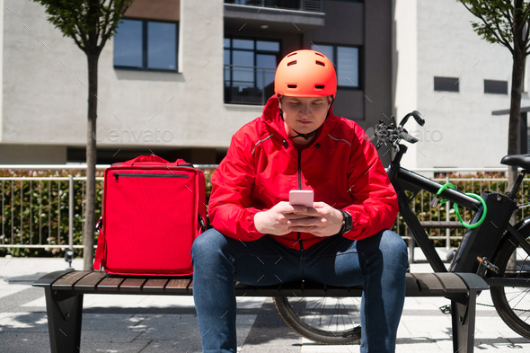 Delivery man checking food order with smartphone Stock Photo by ...
