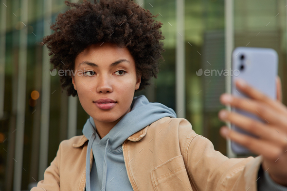 Adorable young Afro American woman clicks sefie images during free time ...