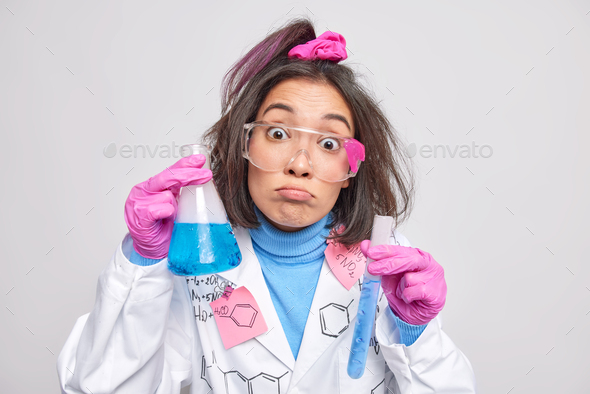 Suprised female scientist conducts experiment with chemicals holds test ...