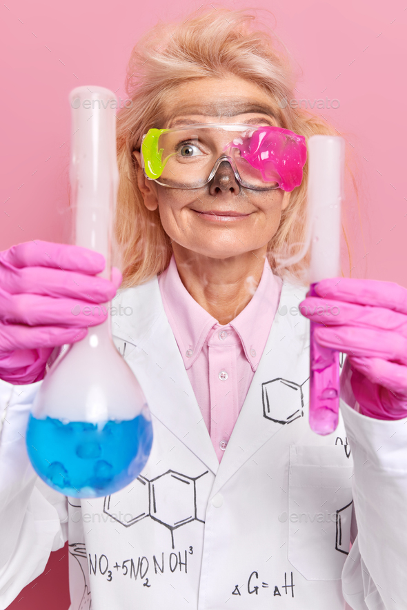 Vertical shot of woman laboratory worker holds glass flask and tube ...