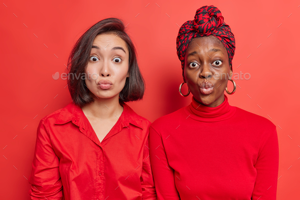 Diverse women best friends stand closely to each other keep lips ...