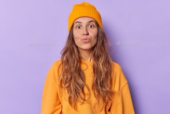 Photo of romantic young woman with folded lips looks surprisingly at ...