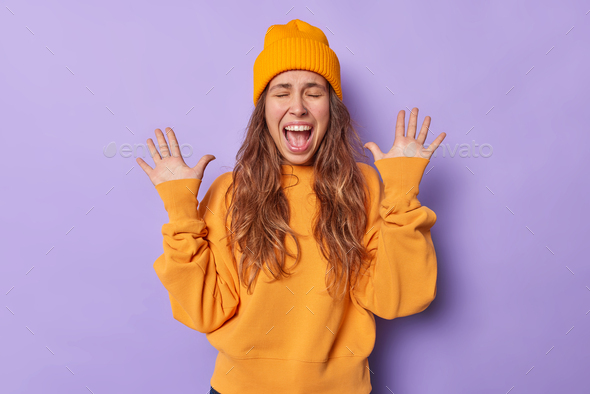 Indoor Shot Of Happy Long Haired Young European Woman Raises Palms