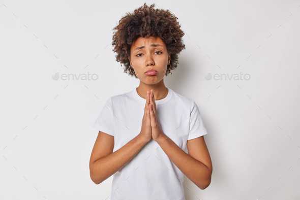 Dissatisfied curly haired young woman begs for favor looks with ...