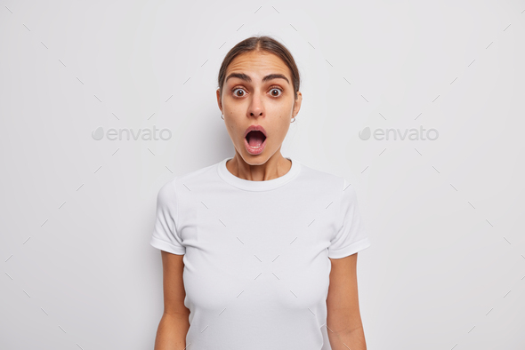 Portrait of shocked young European woman with bated breath keeps mouth ...
