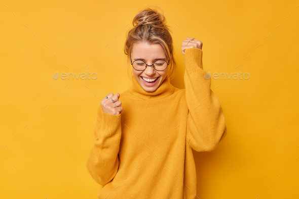 Yes finally success. Positive woman raises arms with clenched fists ...