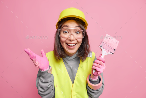 Positive female maintenance worker ready to work poses with painting ...