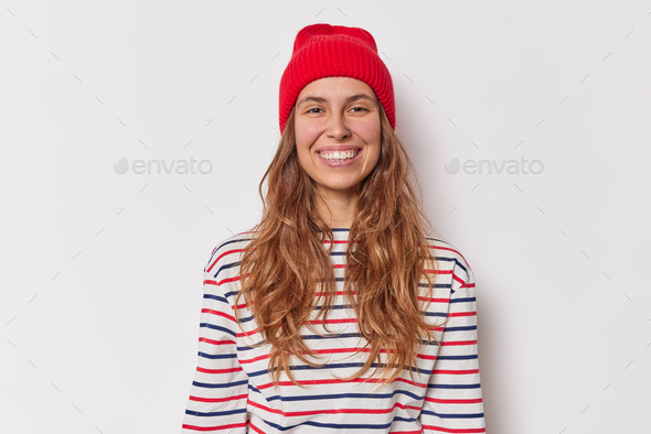 Portrait of good looking young woman smiles happily looks joyfully has ...