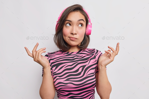 Maybe yes or no. Hesitant young Asian woman shrugs shoulders has ...