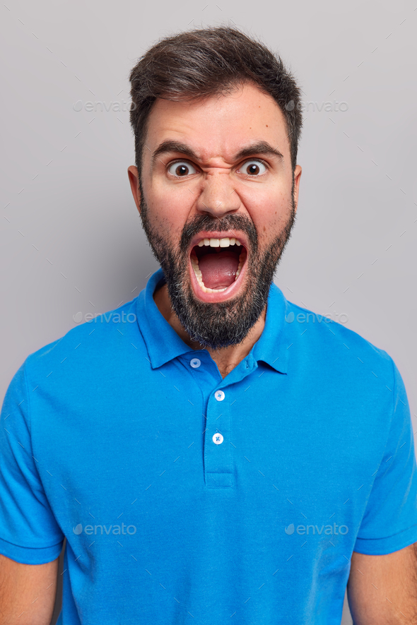 Outraged pissed bearded European man shouts angrily keeps mouth widely ...