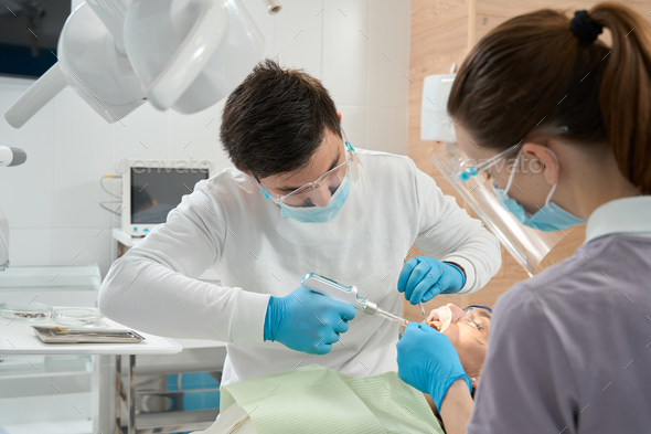 Stomatologist giving anesthesia to client using dental syringe gun ...