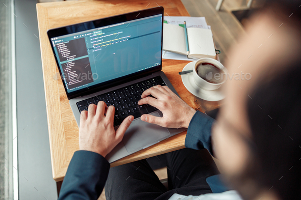 Back view of developer programmer freelancer working on project in cafe ...