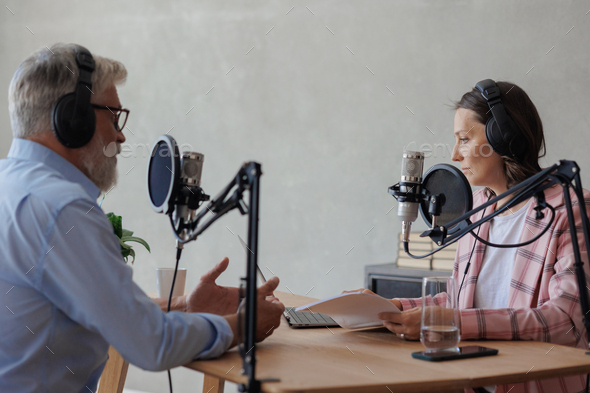 older man and female presenter in a recording studio create a podcast ...