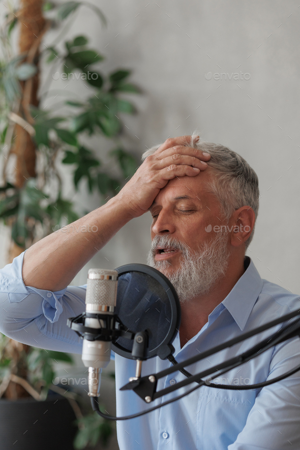 elderly man with gray hair is recording podcast in a recording studio ...