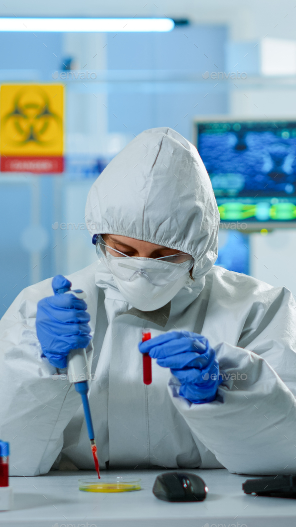 Science technician in ppe suit using micropipette and petri dish ...