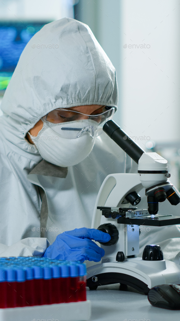 Woman scientist in ppe suit working in lab using modern microscope ...