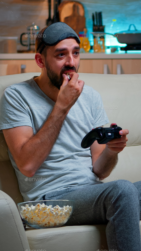 Upset pro gamer sitting on couch and playing soccer videogames Stock ...