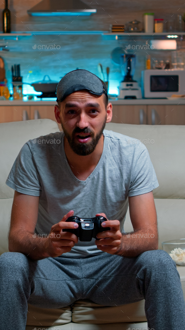 Upset pro gamer sitting in front of television losing soccer video ...