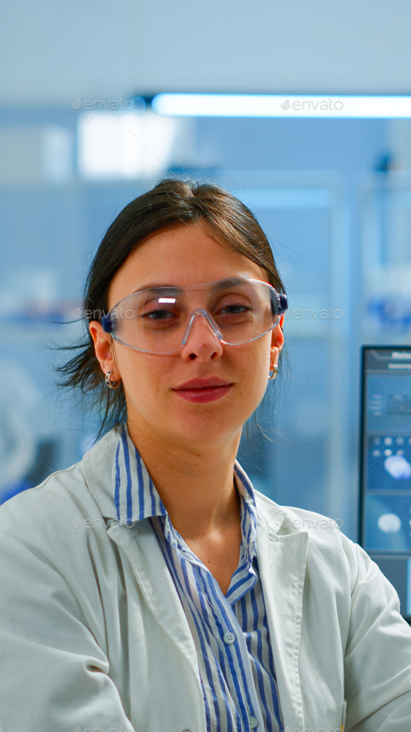 Chemist with lab coat sitting in laboratory looking at camera smiling ...