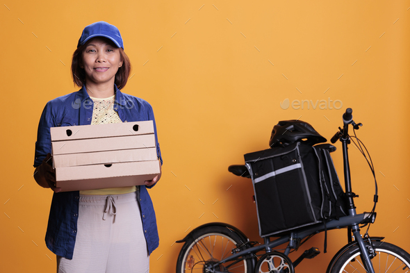 Restaurant worker wearing blue uniform holding stack of pizza ...