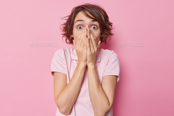 Shocked terrified European woman popping eyes covers mouth with palms ...