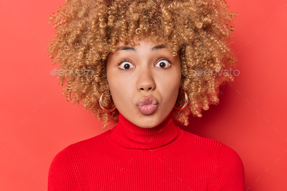 Shocked young emotional young woman has widely opened eyes keeps lips ...
