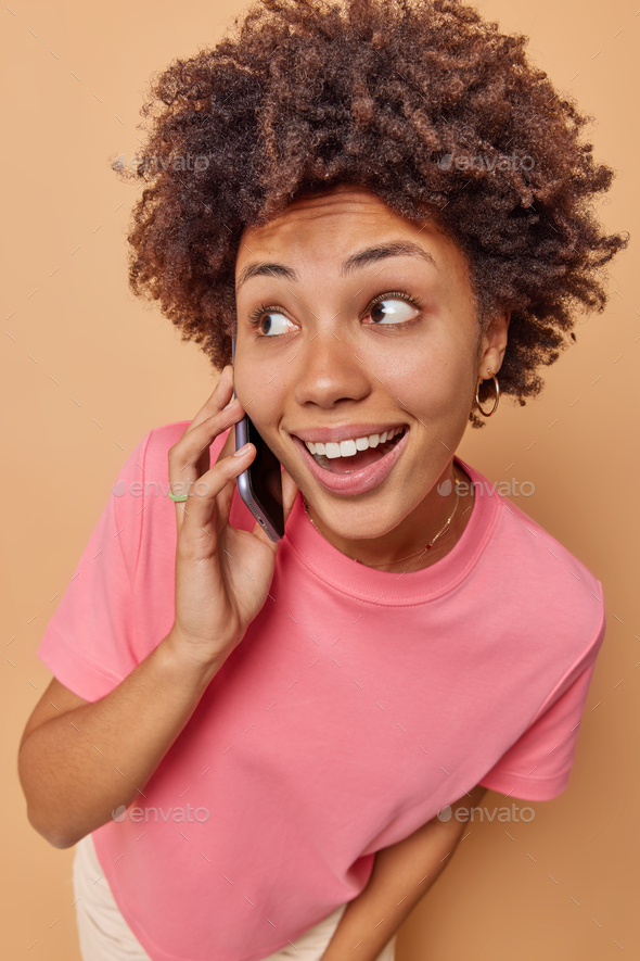Happy surprised young woman has telephone conversation focused away ...