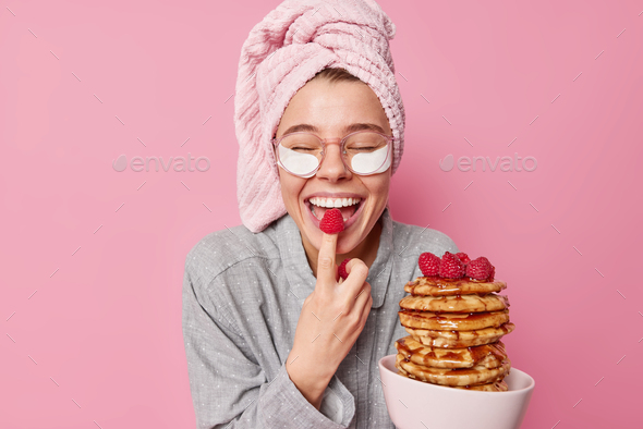 Positive European woman eats delicious pancakes poses with raspberry on ...