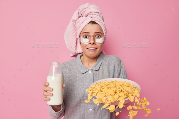 Stressed young woman looks embarrassed poses with cornflakes spilled ...