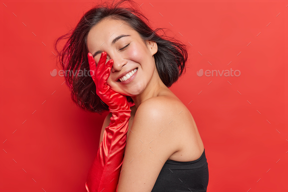 Sideways shot of happy Asian woman keeps eyes closed smiles tenderly ...