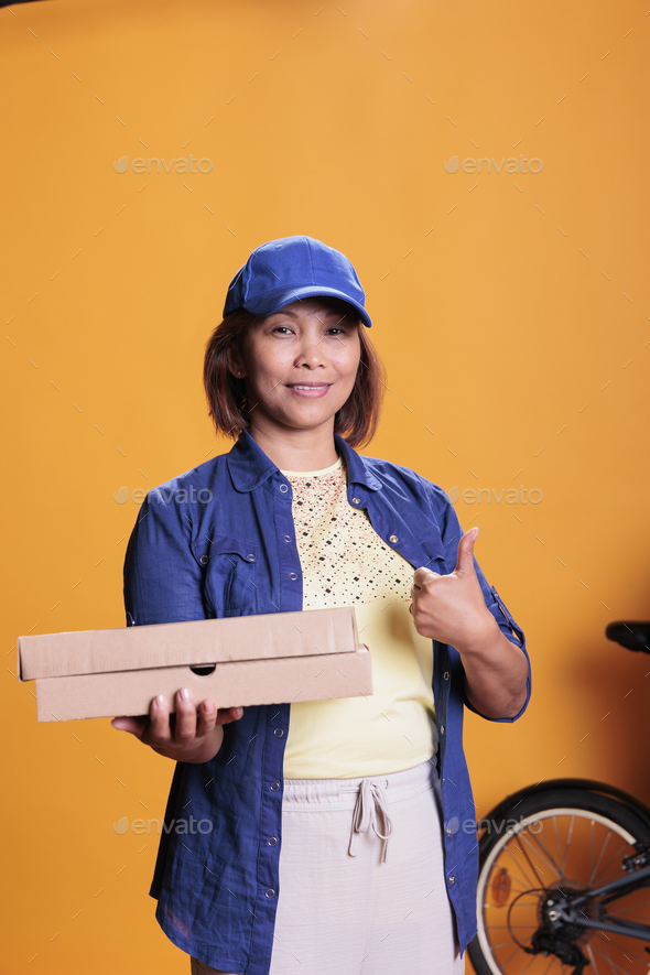 Smiling pizzeria delivery employee doing approval sign while delivering ...